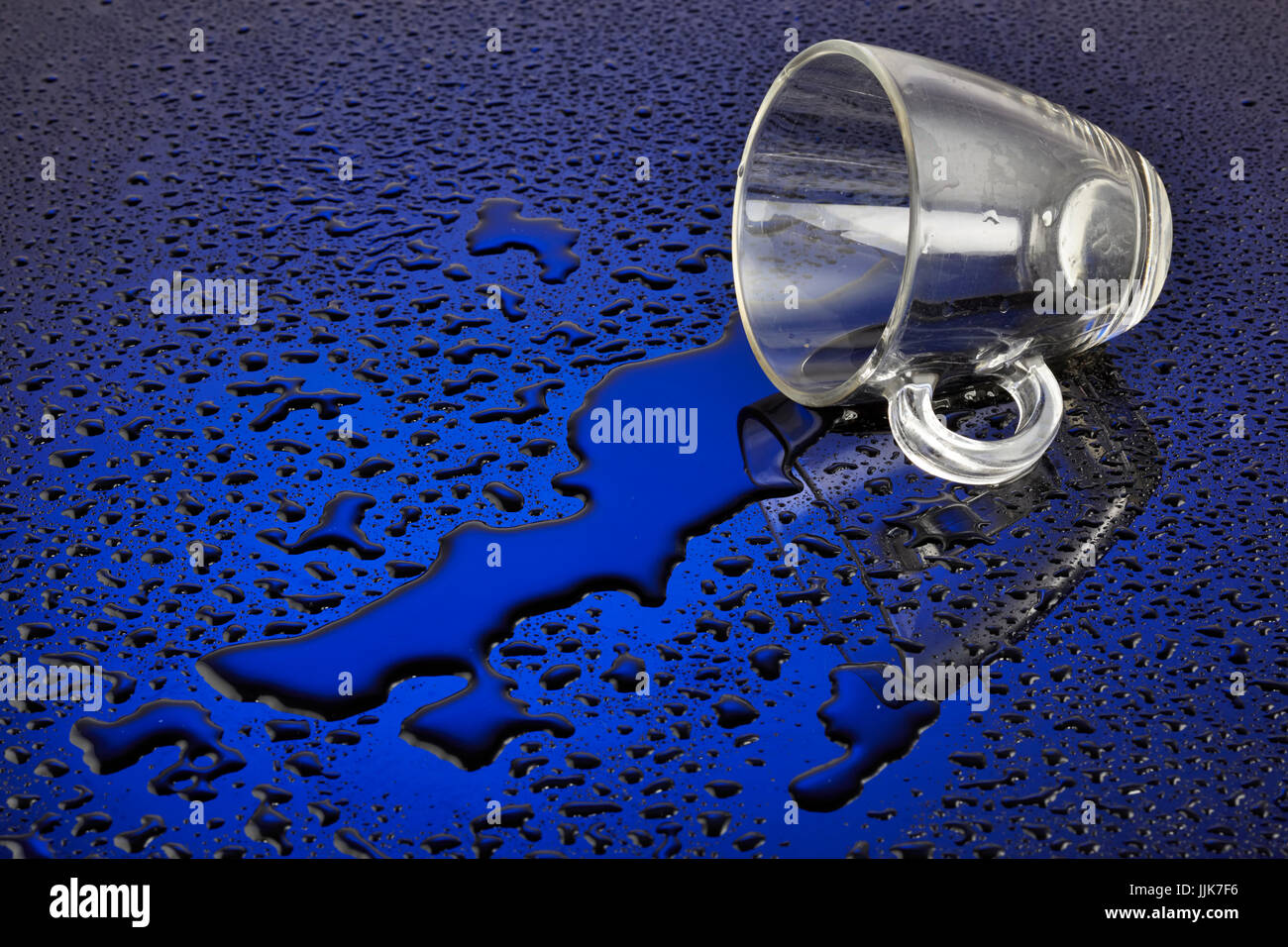 Glass of water spilled with drops on light background Stock Photo - Alamy