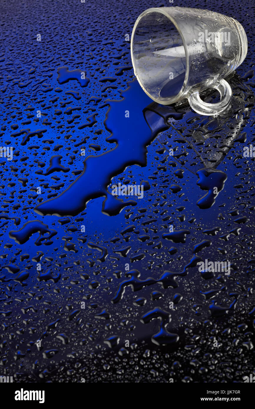 Glass of water spilled with drops on light background Stock Photo - Alamy