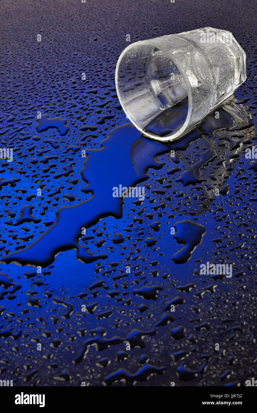 Glass of water spilled with drops on light background Stock Photo - Alamy