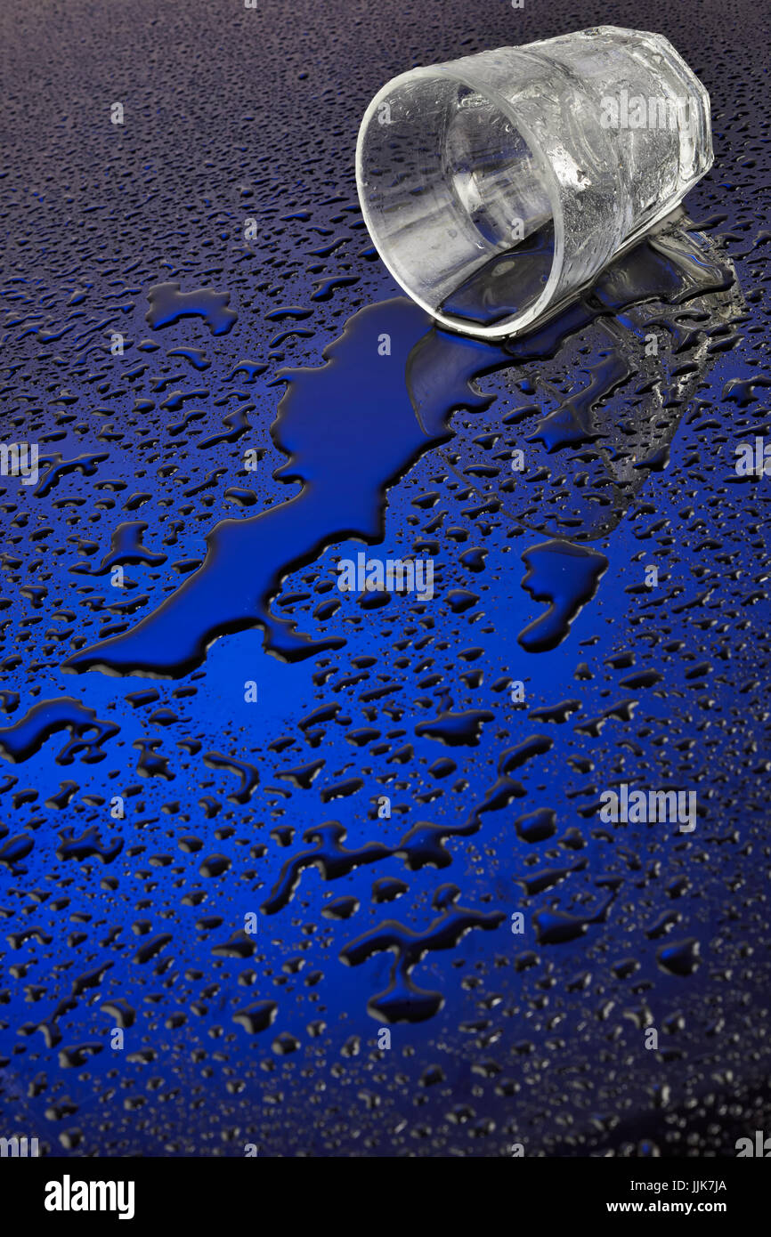 Glass of water spilled with drops on light background Stock Photo - Alamy