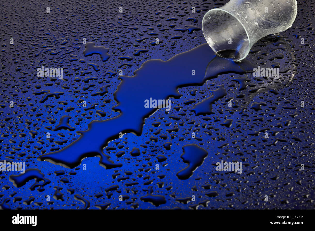 Glass of water spilled with drops on light background Stock Photo - Alamy