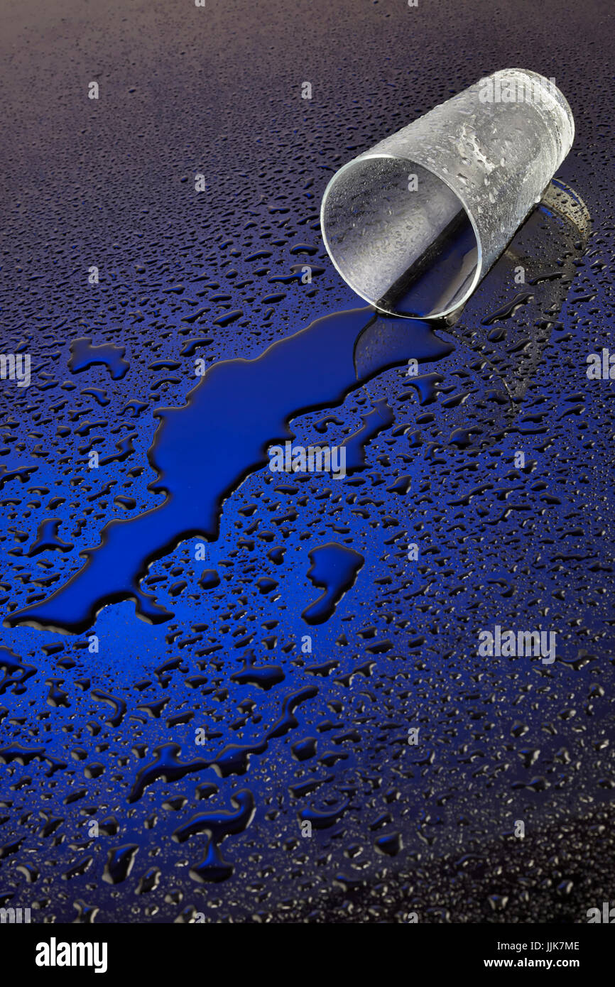 Glass of water spilled with drops on light background Stock Photo - Alamy