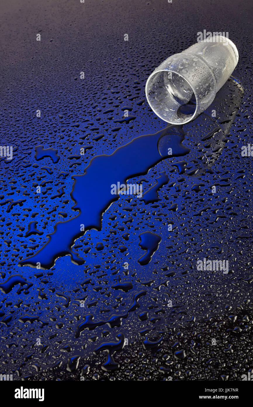 Glass of water spilled with drops on light background Stock Photo - Alamy