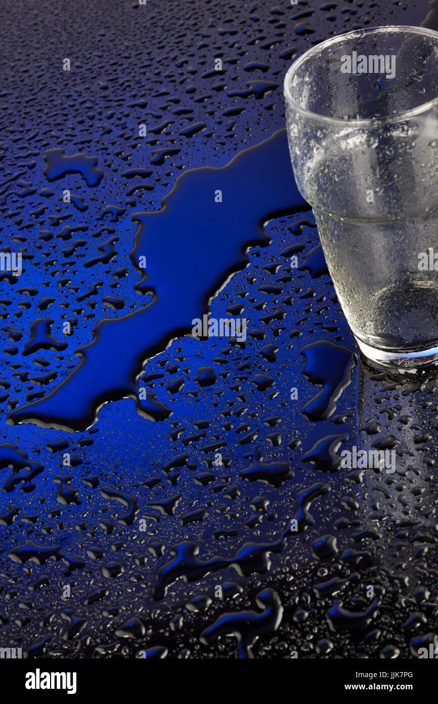 Glass of water spilled with drops on light background Stock Photo - Alamy