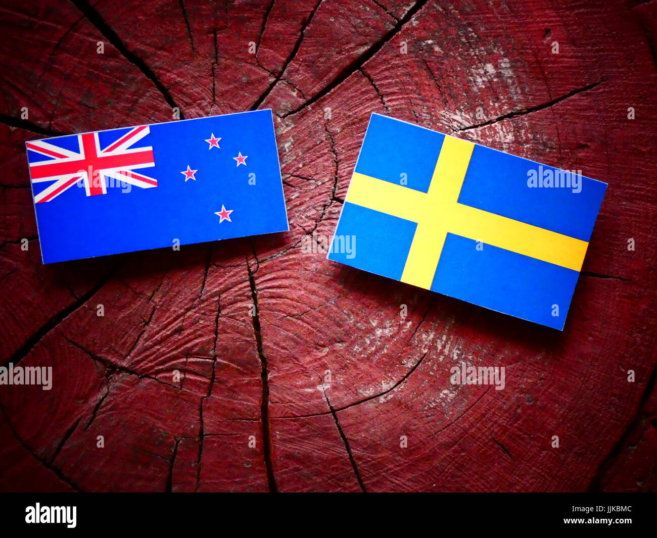 New Zealand flag with Swedish flag on a tree stump isolated Stock Photo ...