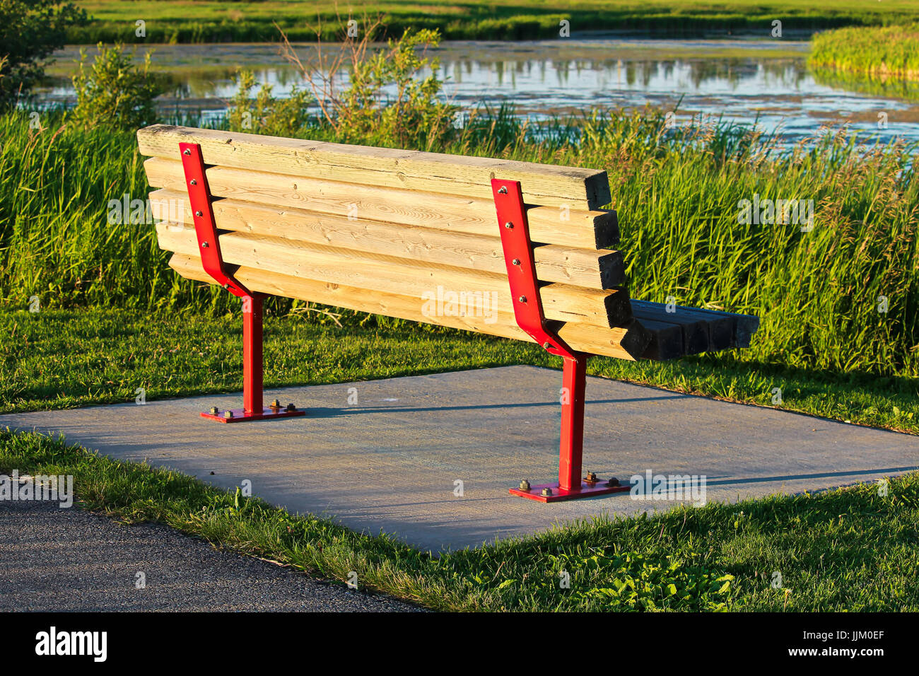 A park bench on a concrete base overlooking a scenic marsh Stock Photo ...