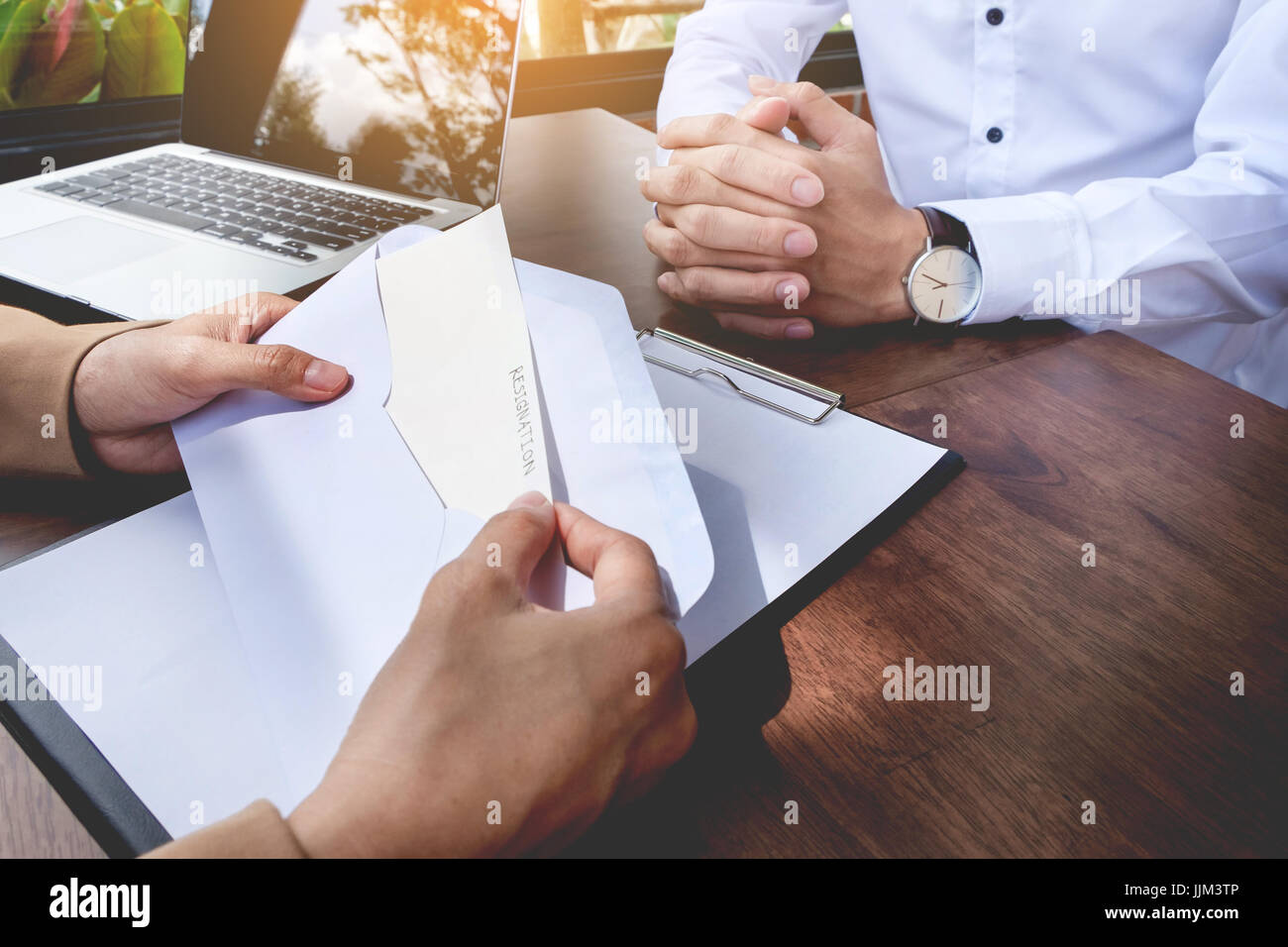 Hand of a businessman hands over a resignation letter on a wooden table ...