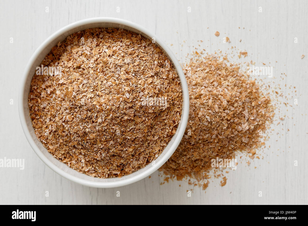 Wheat bran in white ceramic bowl isolated on painted white wood from ...