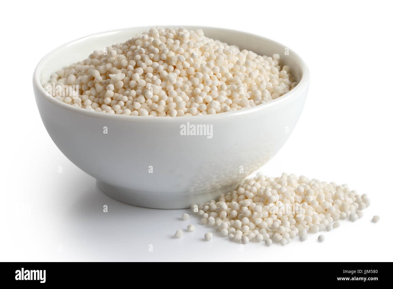 Dry tapioca pearls in white ceramic bowl isolated on white. Spilled ...