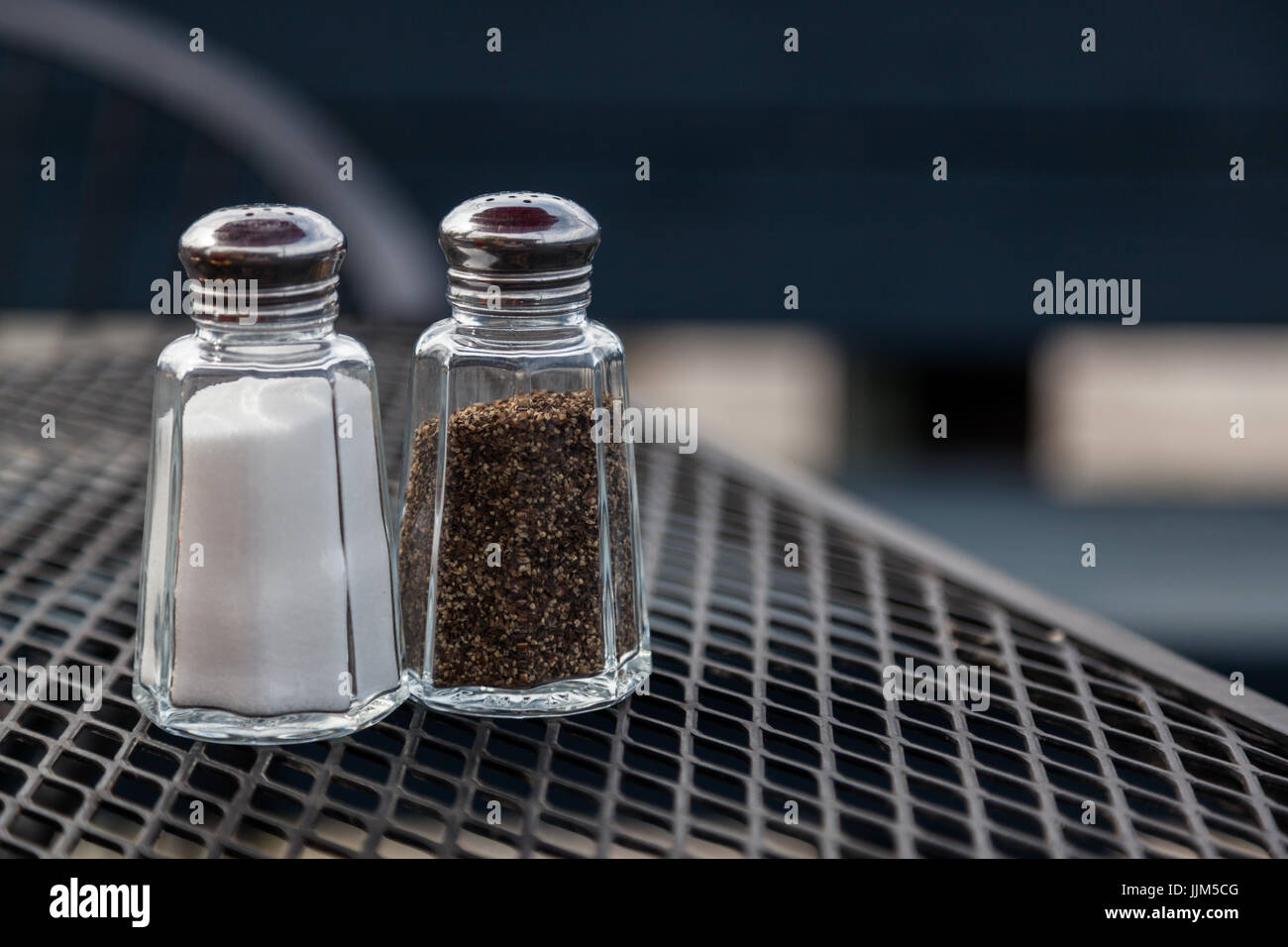 Glass holders full of salt and pepper sit on a patio table of a ...