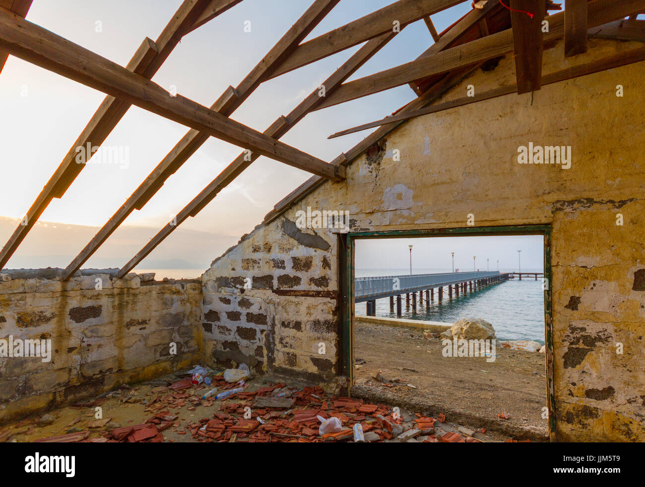 Pier and sea view through derelict house window by the beach in Argaka ...
