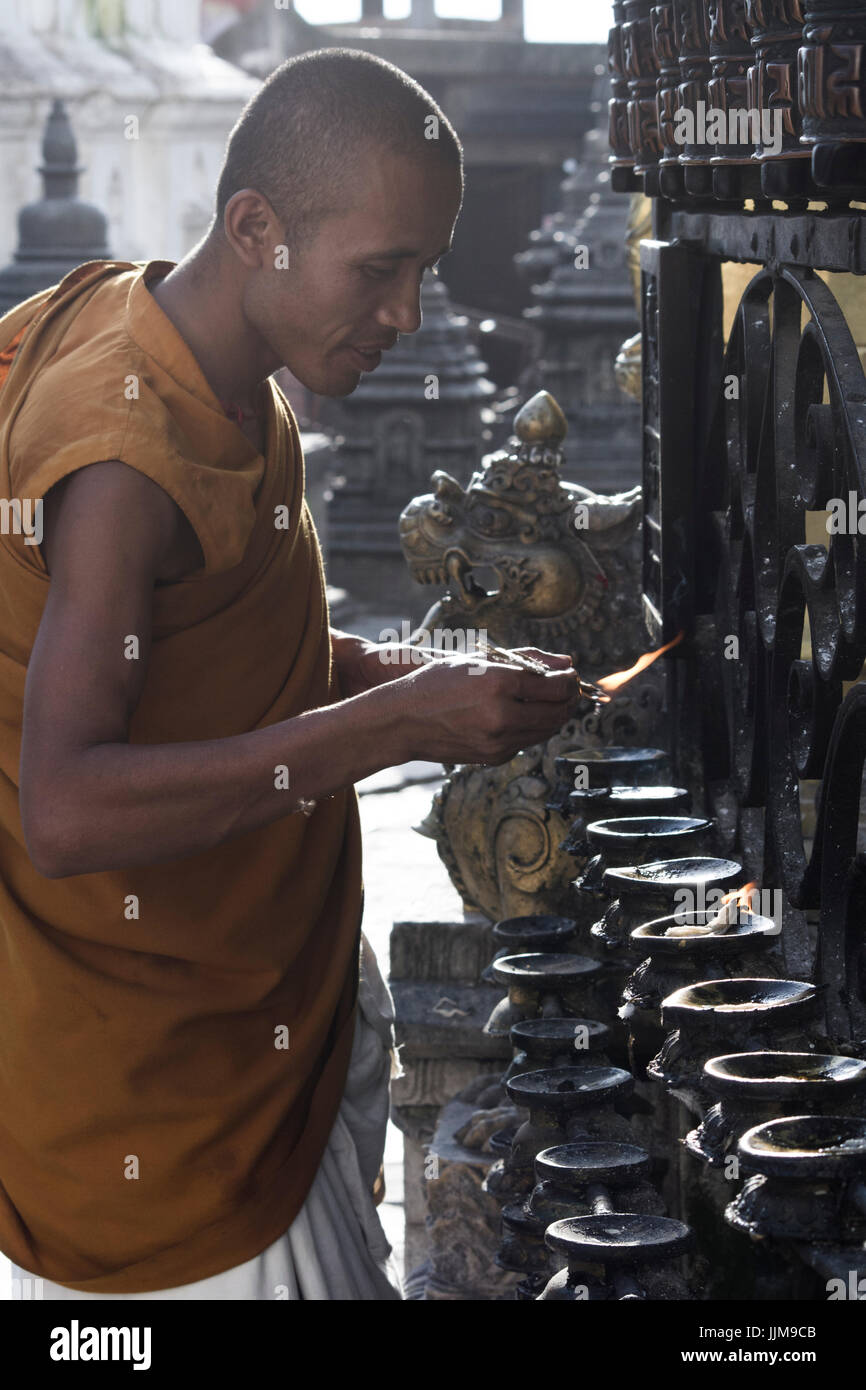Kathmandu, Nepal. Buddhist monk lights lamps at Swayambhunath temple ...