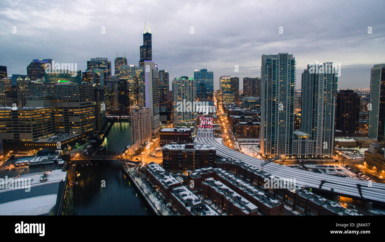 A snow covered railway and Chicago skyline lights at dusk during winter ...
