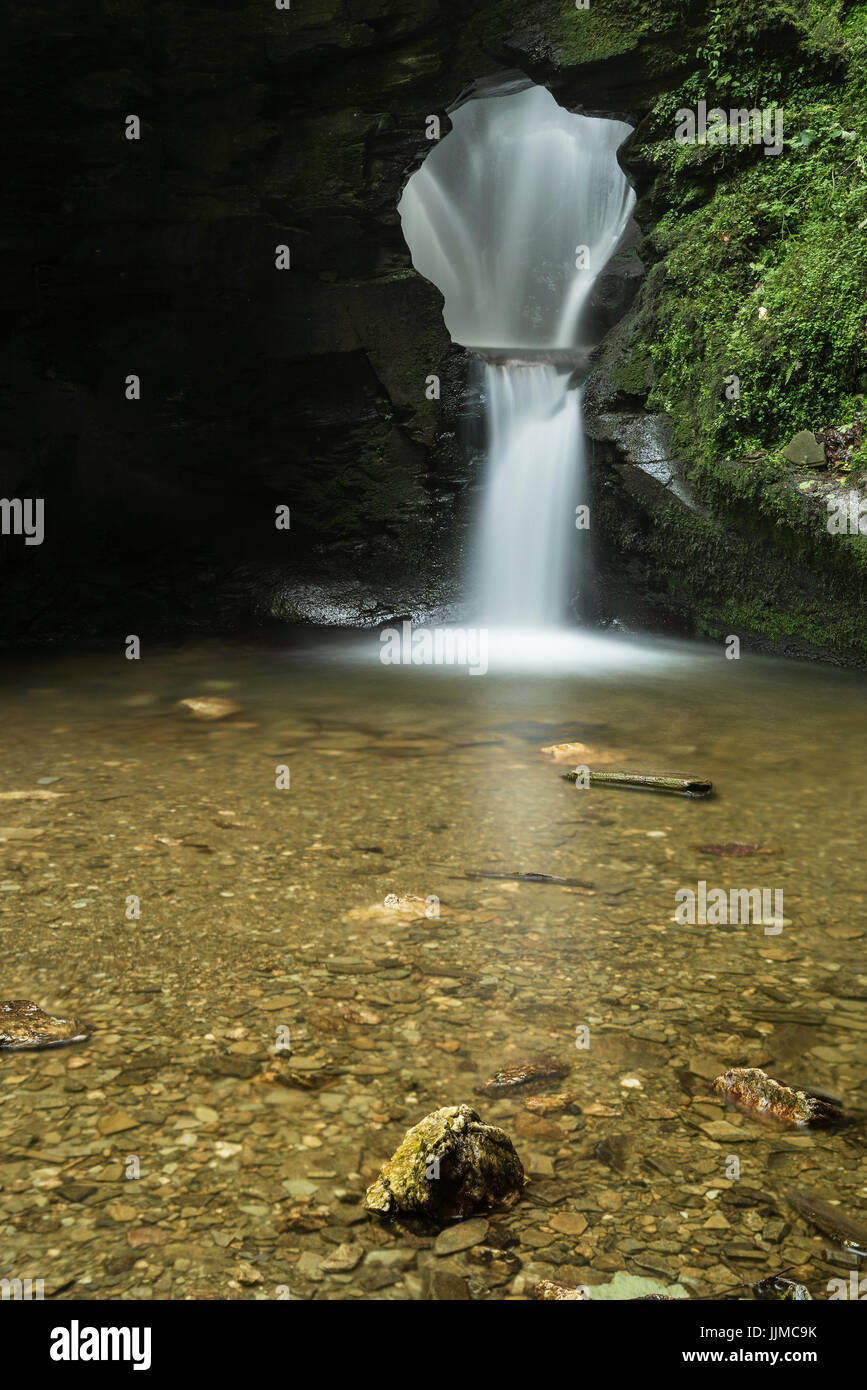 Beautiful flowing waterfall with magical fairy tale feel in lush green ...