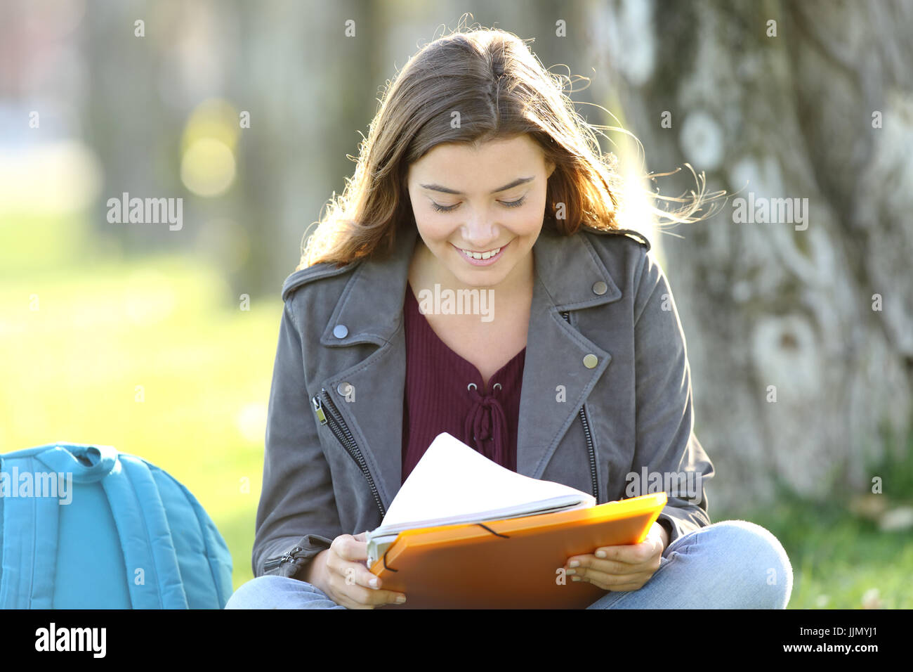 Single student girl studying reading notes sitting on the grass in a ...