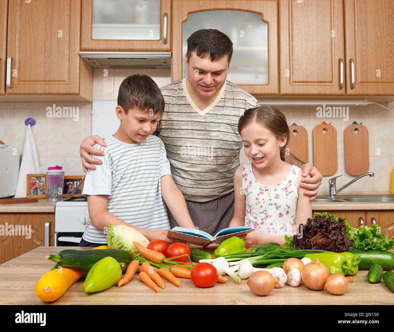 Father and two children reading cooking book and choice dishes. Happy ...
