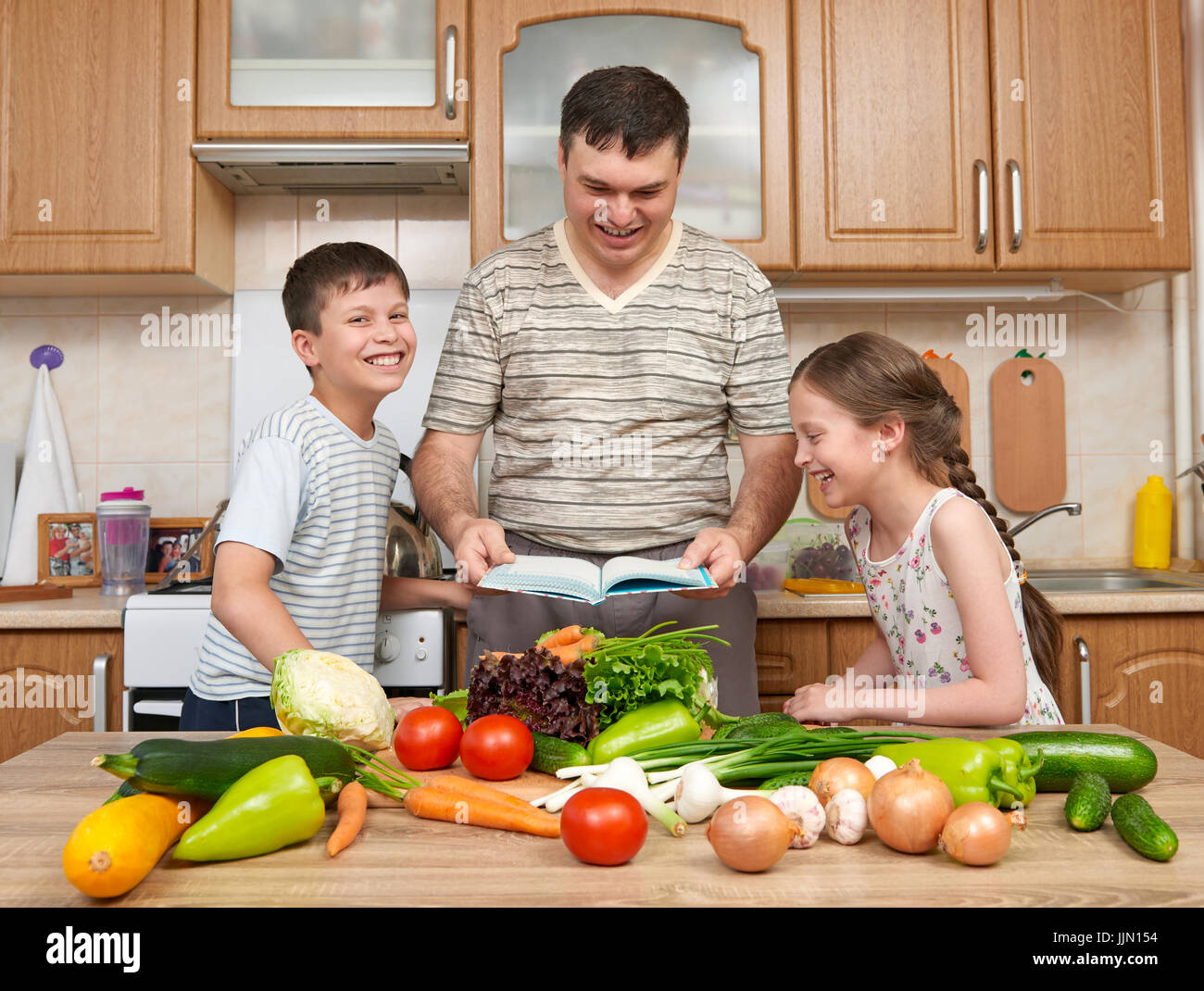 Father and two children reading cooking book and choice dishes. Happy ...