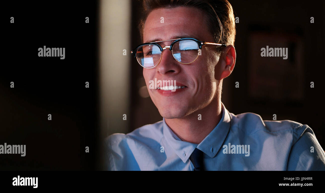 Young man working on computer at night in dark office. The designer ...