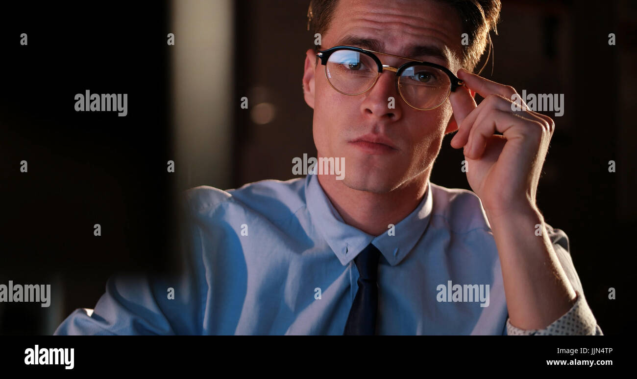 Young man working on computer at night in dark office. The designer ...