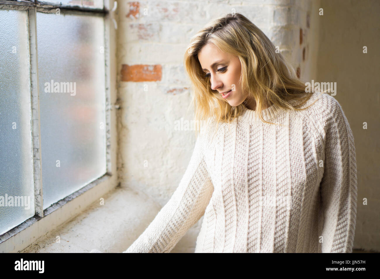 Beautiful young woman looking out of the window smiling Stock Photo - Alamy