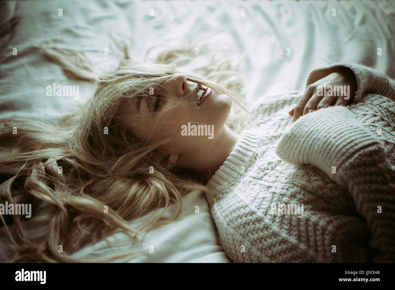 Tired young woman laying down in bed Stock Photo - Alamy