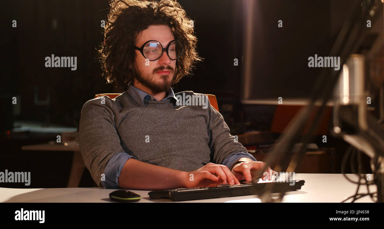 Young man working on computer at night in dark office. The designer ...