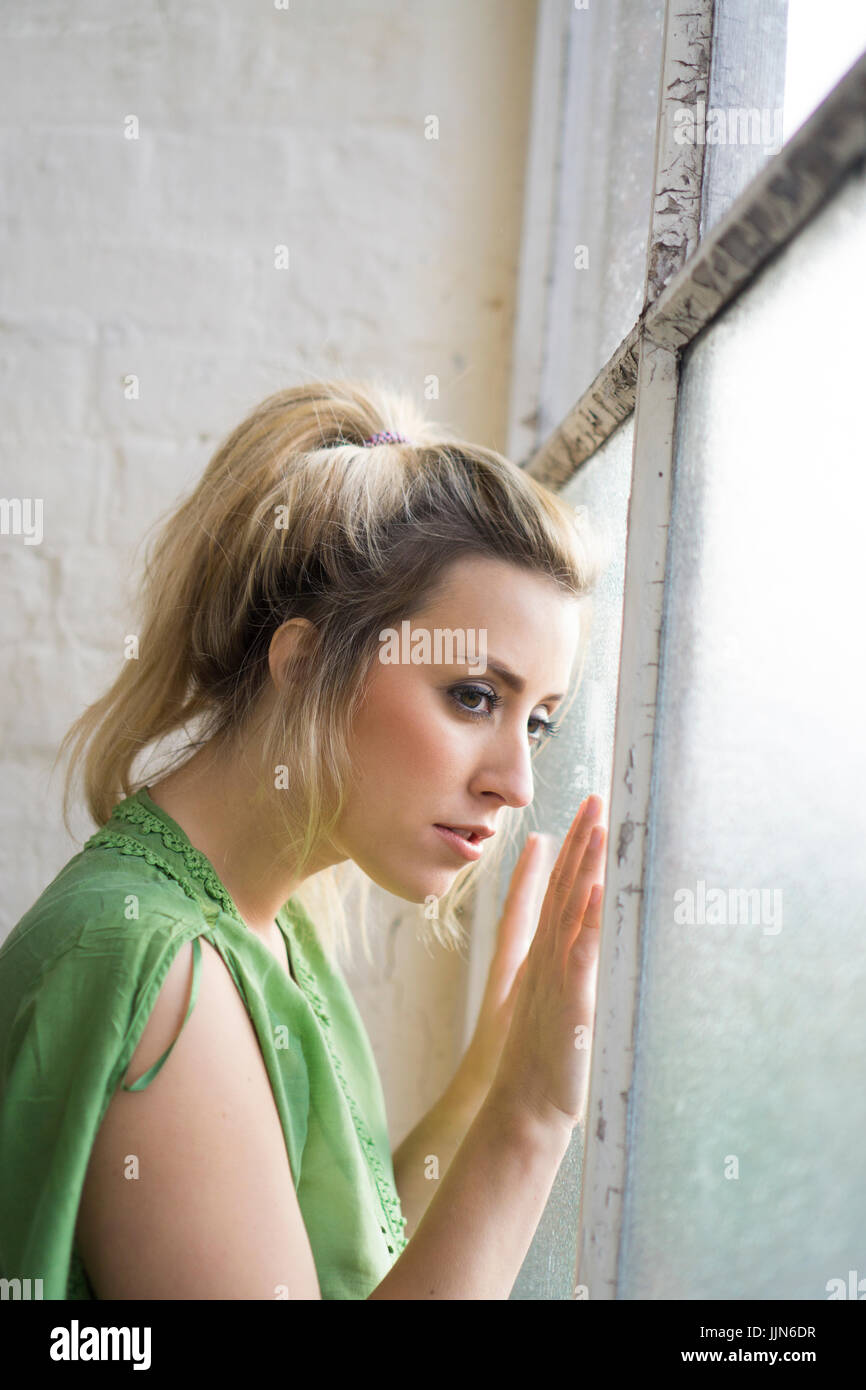 Worried young woman looking out of the window Stock Photo - Alamy