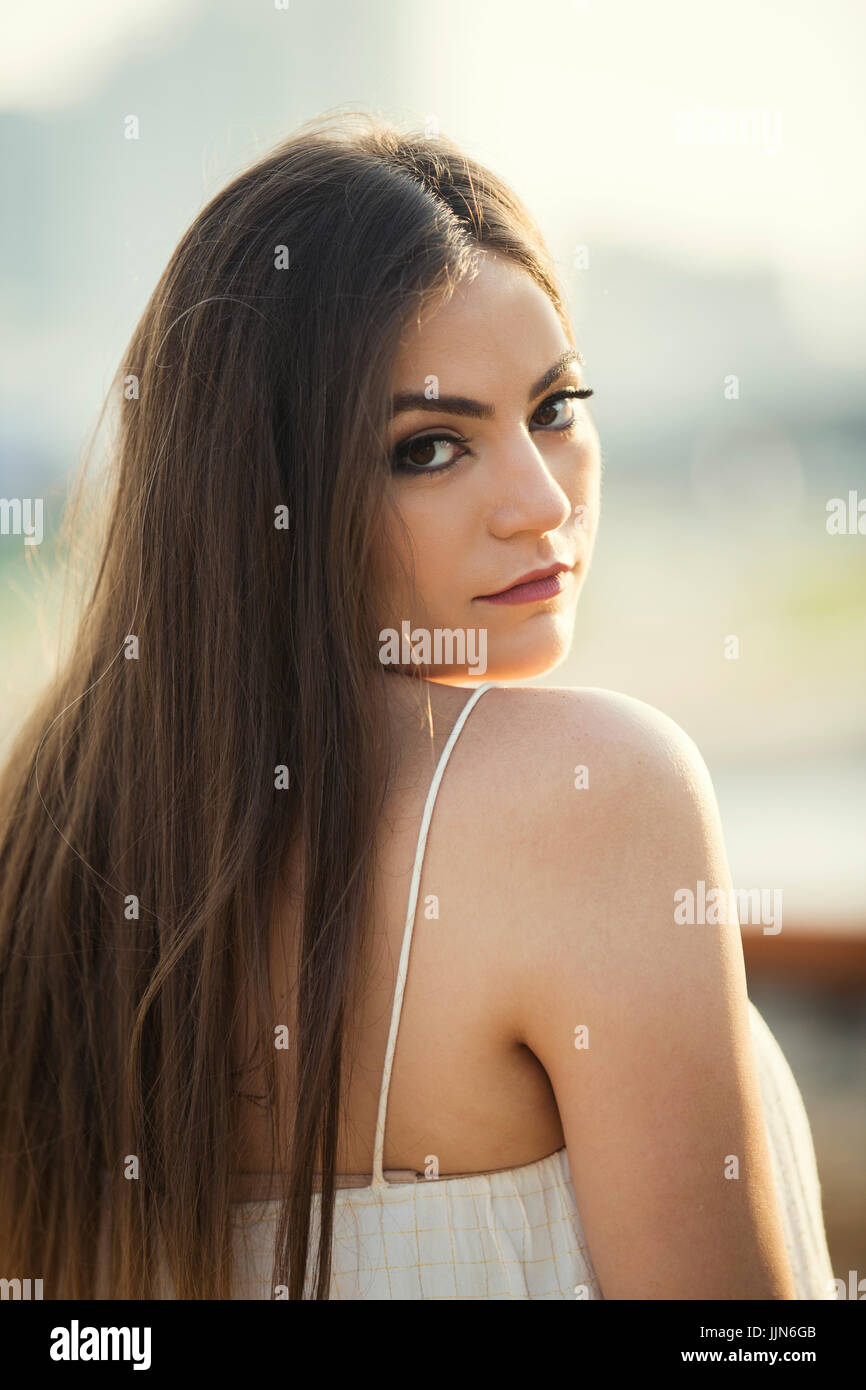 Beautiful young woman looking over shoulders outdoors Stock Photo - Alamy