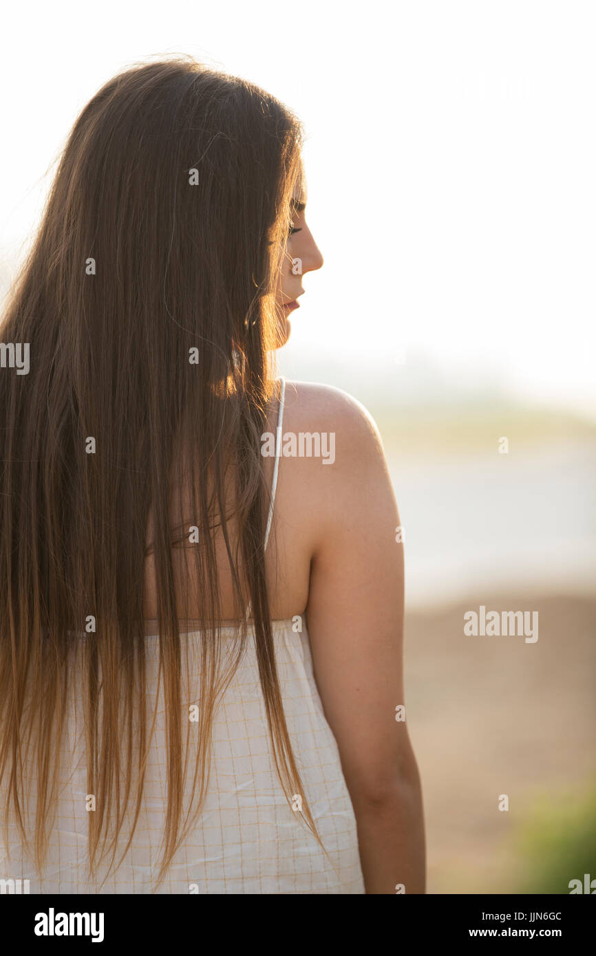 Serious young woman standing outdoors looking over shoulder Stock Photo ...