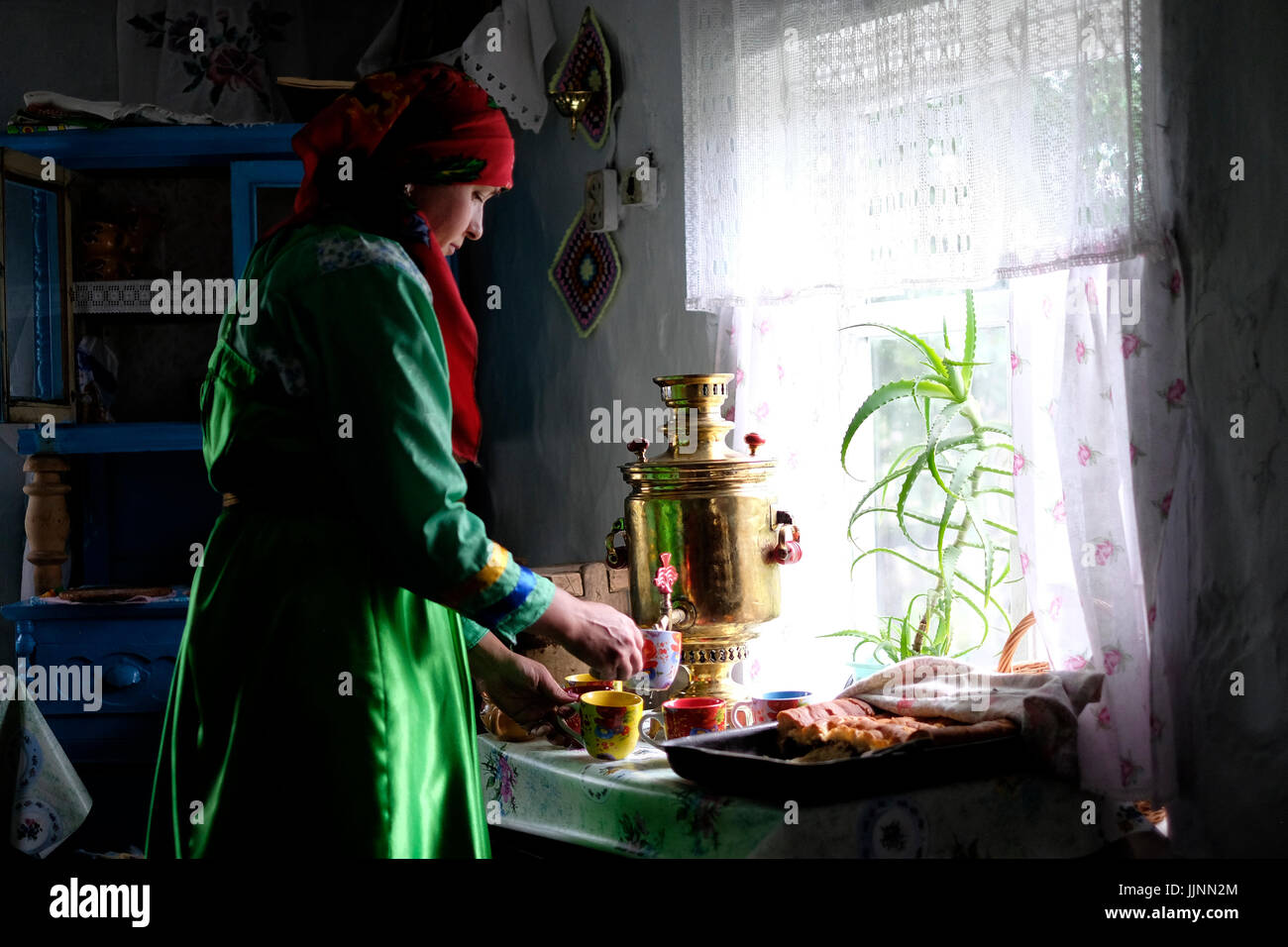 A Russian woman wearing traditional sarafan dress prepares tea in ...