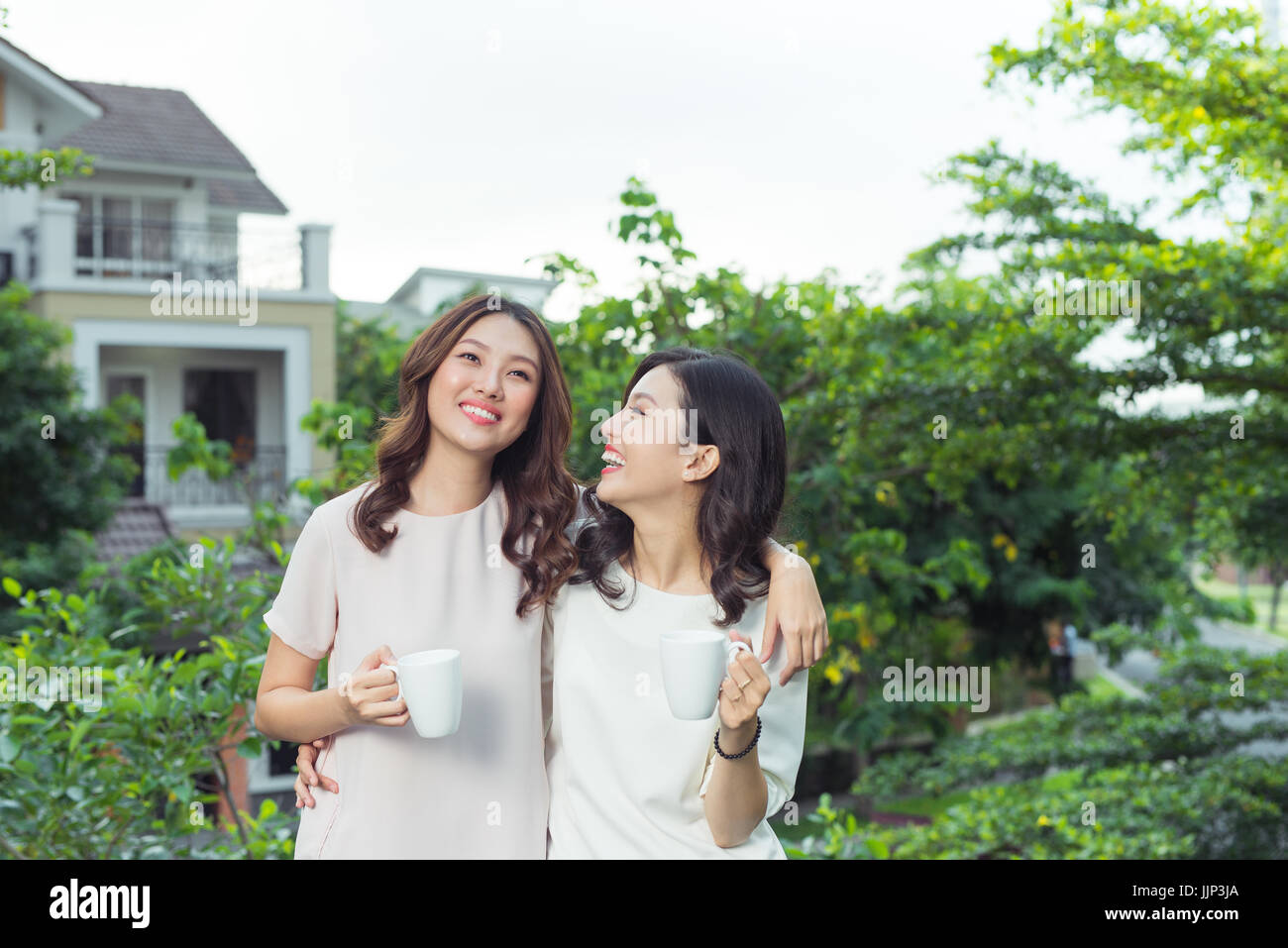 Happy young women friends well-dressed smiling while standing together ...
