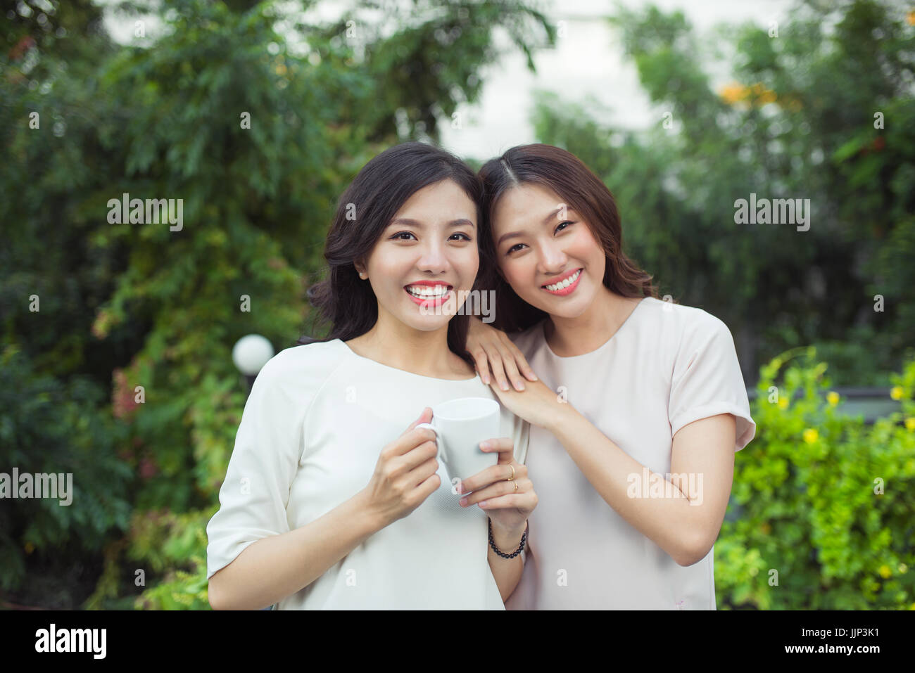 Happy young women friends well-dressed smiling while standing together ...