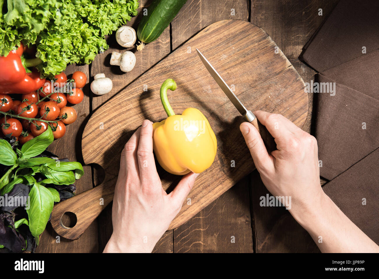Above view of human hands cutting pepper on chopping board with group ...