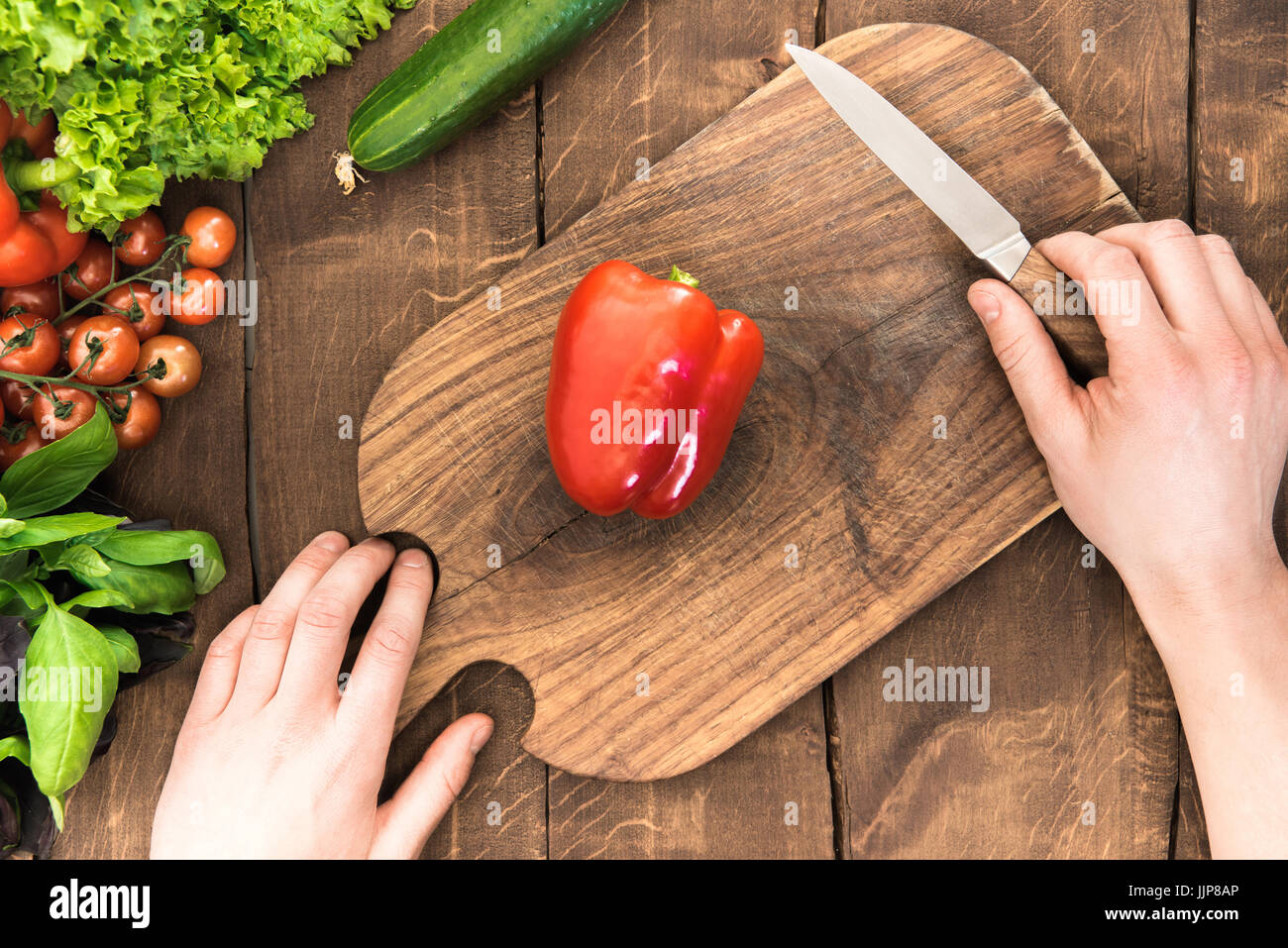 Top view of human hands cutting pepper on chopping board with group of ...