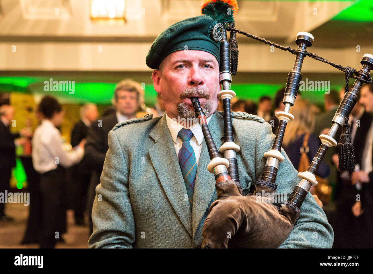 A bag pipe player in traditional costume playing at a social event ...