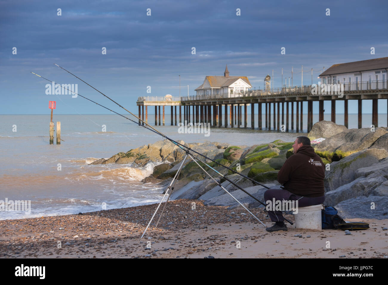 Angler at Sole Bay with Southwold pier behind Stock Photo - Alamy