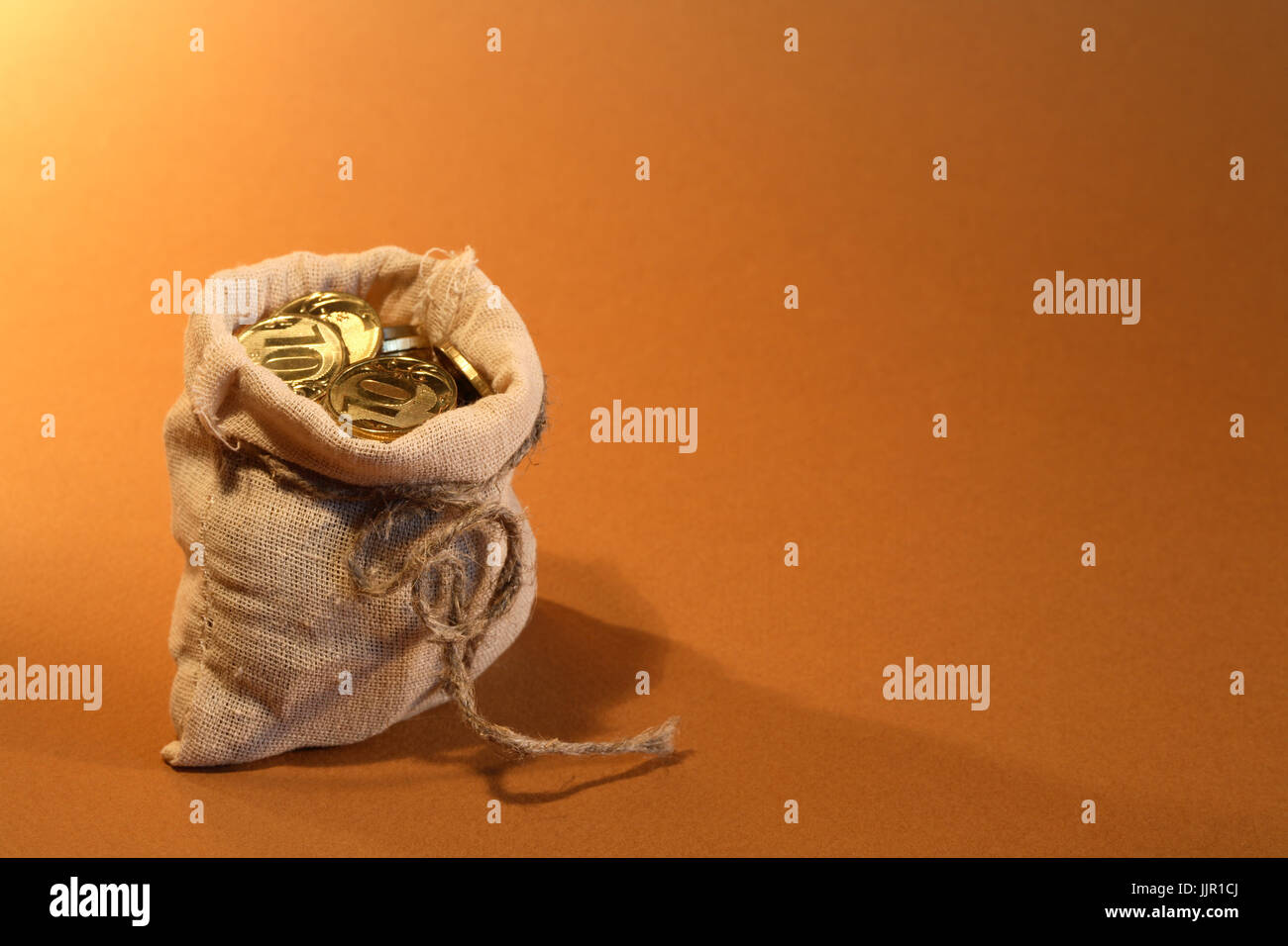 Wealth concept. Open burlap sack full of golden coins standing on nice ...