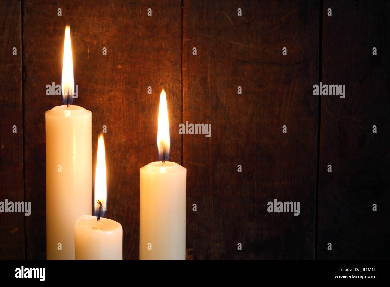 Three ordinary lighting candles against old wooden texture with free ...