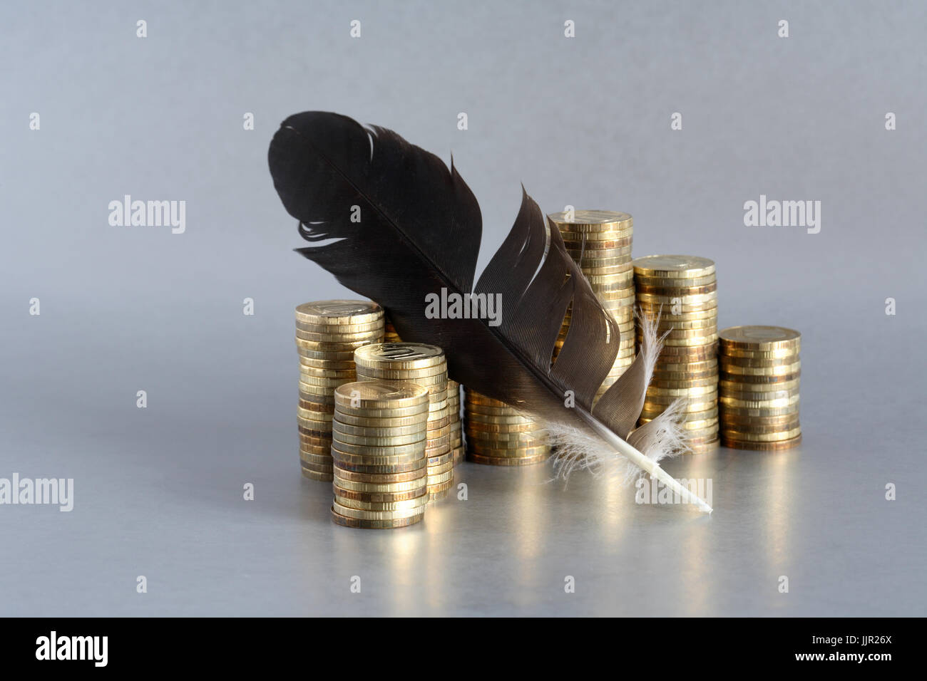 Black quill standing near few coins columns on gray background Stock ...