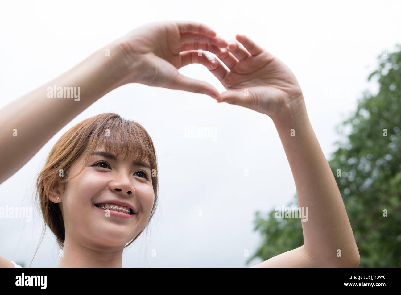 young woman making a heart gesture with her fingers. beautiful asian ...
