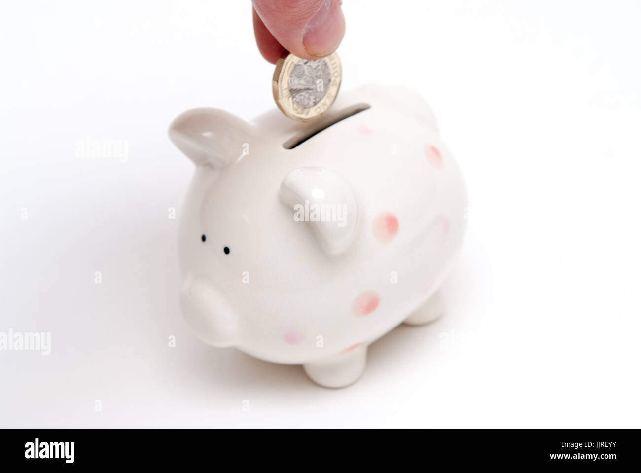 Piggy bank with coin being placed in for savings Stock Photo - Alamy