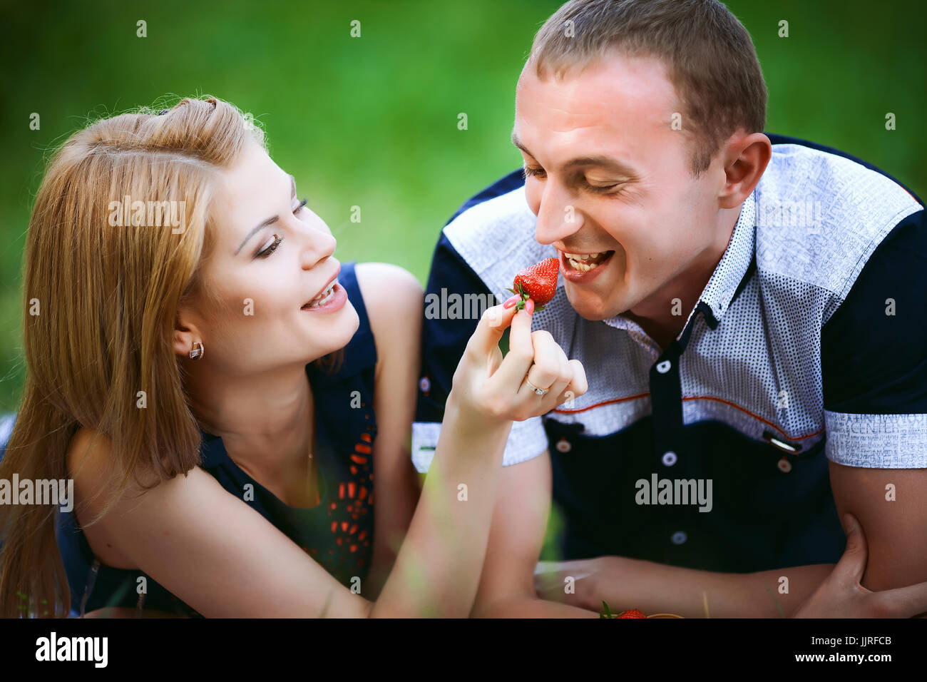 girl feeding the man a strawberry. Beautiful healthy young girlfriend ...