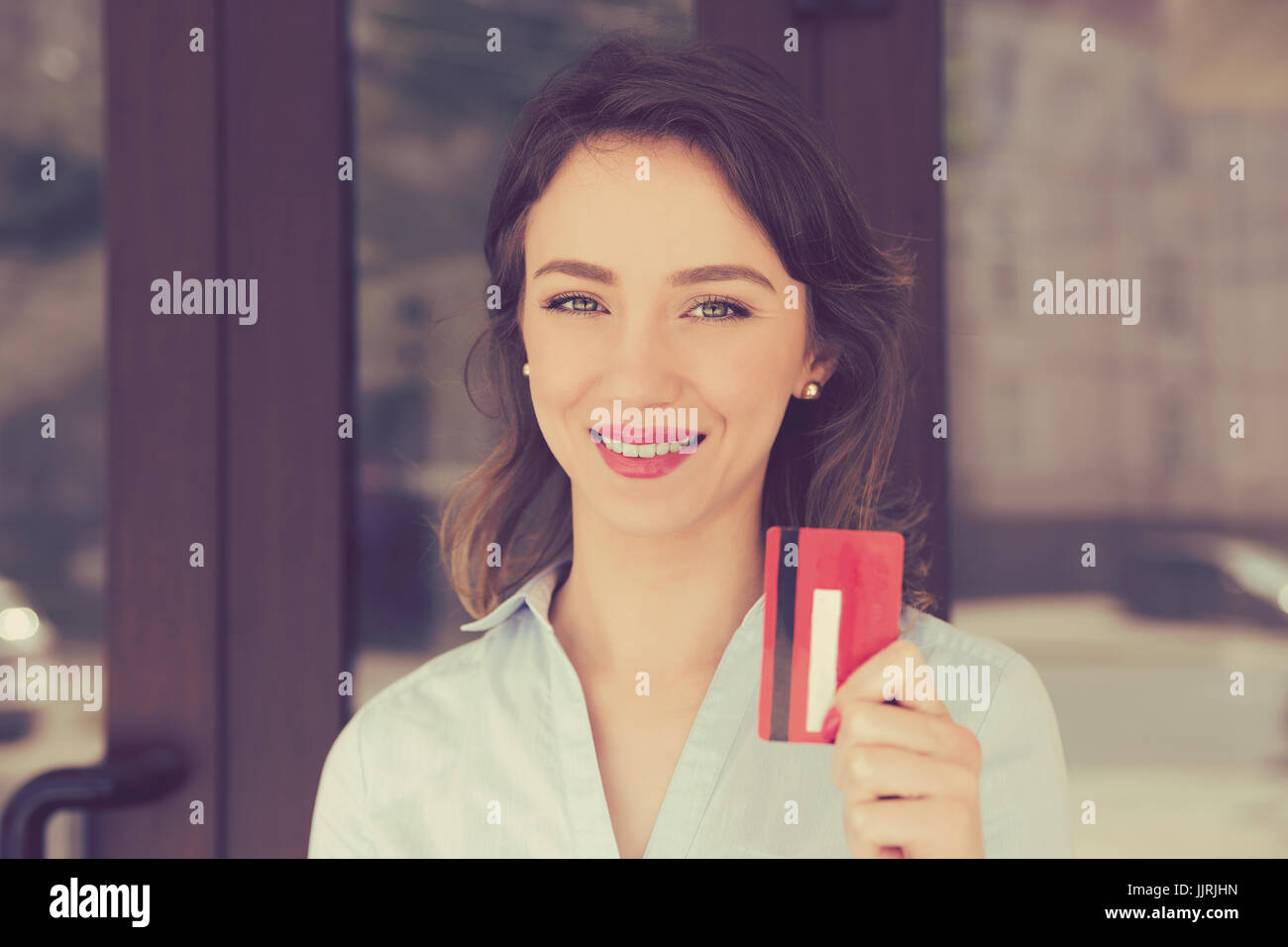Cheerful toothy smile woman holding showing loyalty card near store ... Cheerful toothy smile woman holding showing loyalty card near store ...