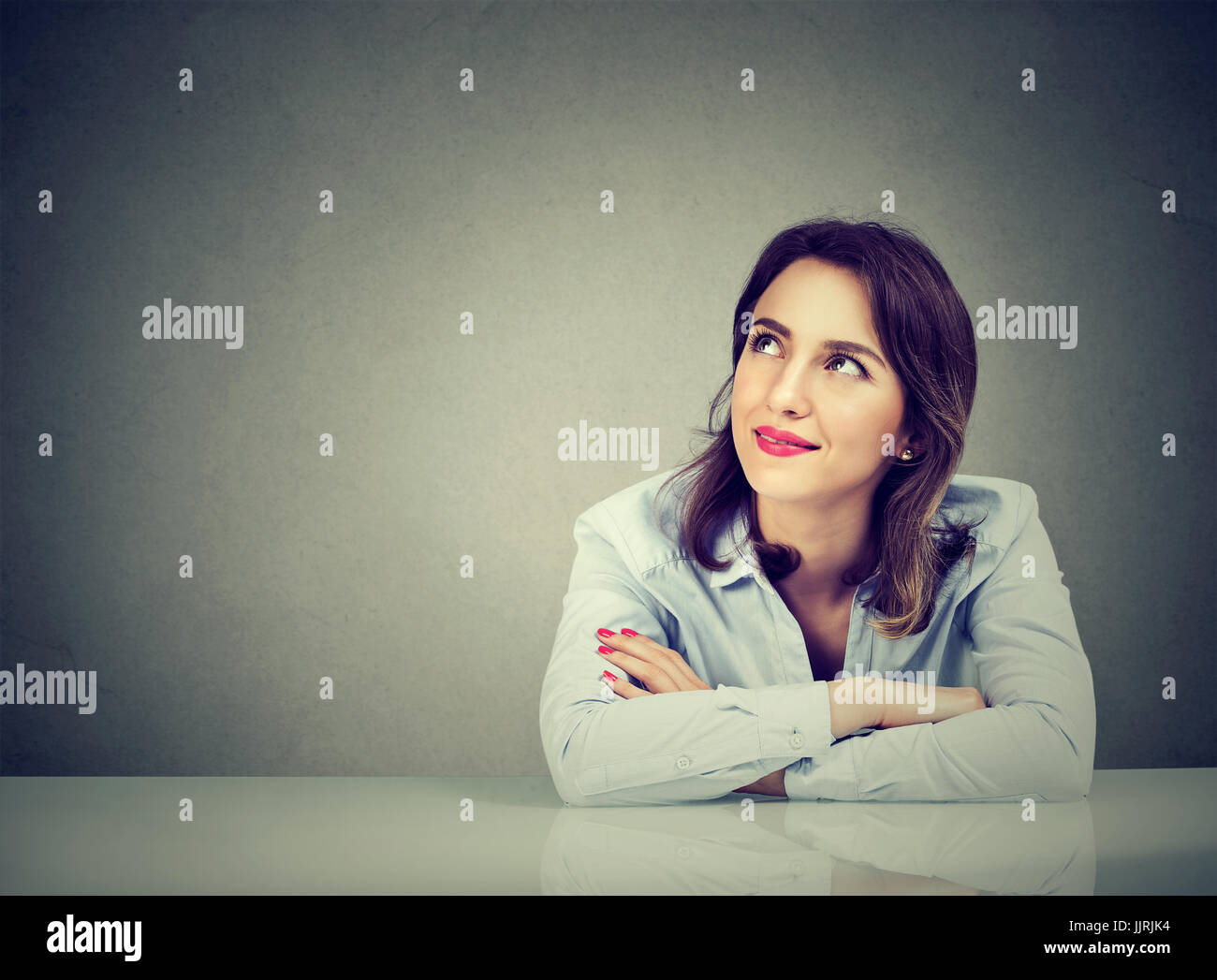 Young woman looking thoughtful and happy Stock Photo - Alamy