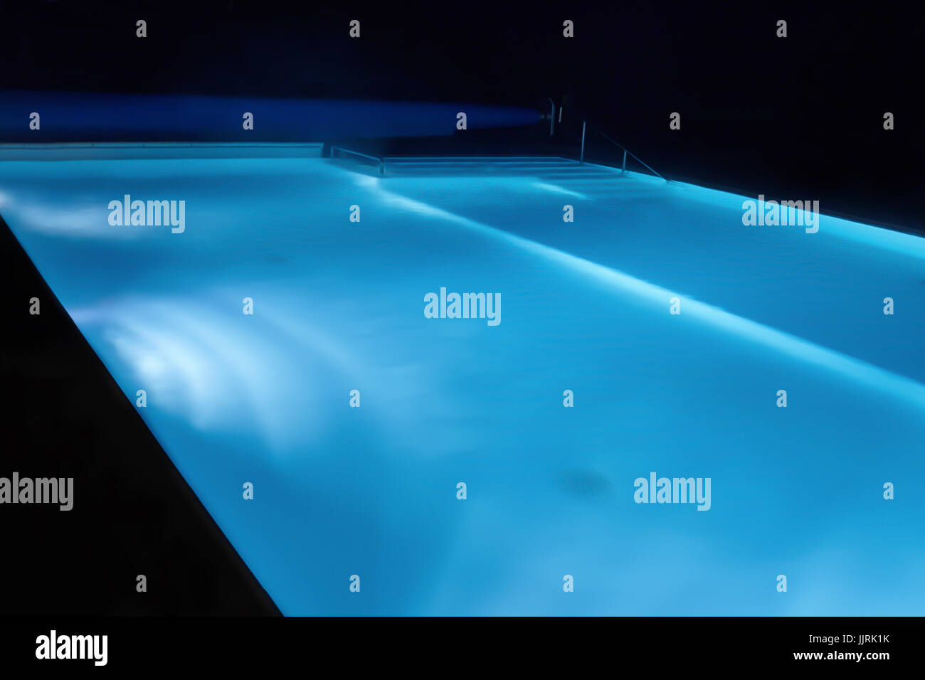 Illuminated blue swimming pool by night Stock Photo - Alamy