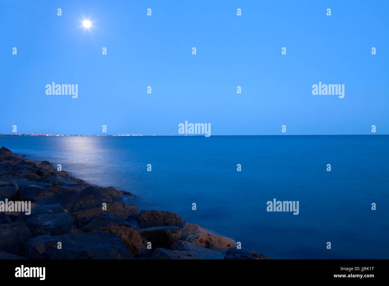 Full moon over the sea at night, long exposure shot with copy space ...