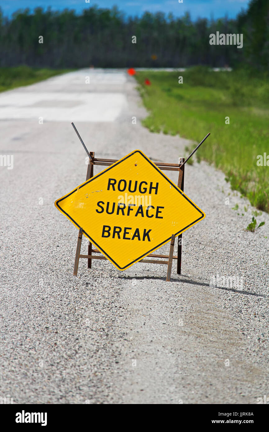 A yellow rough surface break sign with a road blurring into the ...