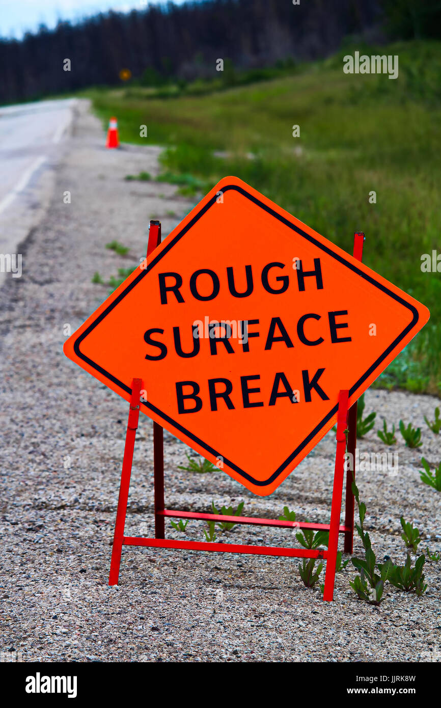 An orange rough surface break sign with construction pylons behind it ...