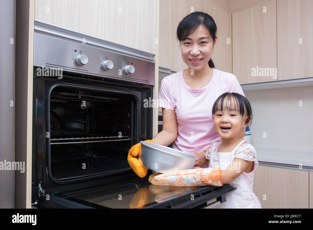 Asian Chinese mother and daughter baking cake together at home in the ...