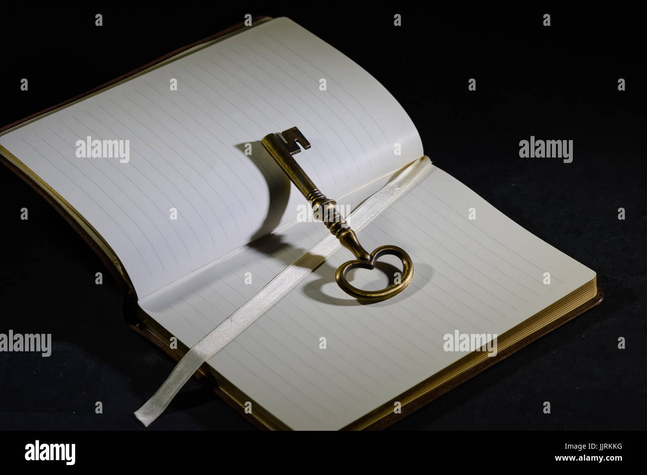 Vintage key in a journal or notebook Stock Photo - Alamy